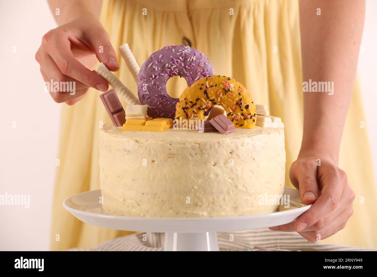 Woman decorating delicious cake with sweets on white background ...