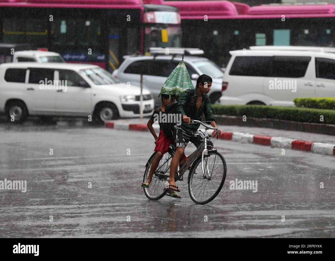 (180530) -- YANGON, May 30, 2018 -- Boys ride bicycle in the rain in ...