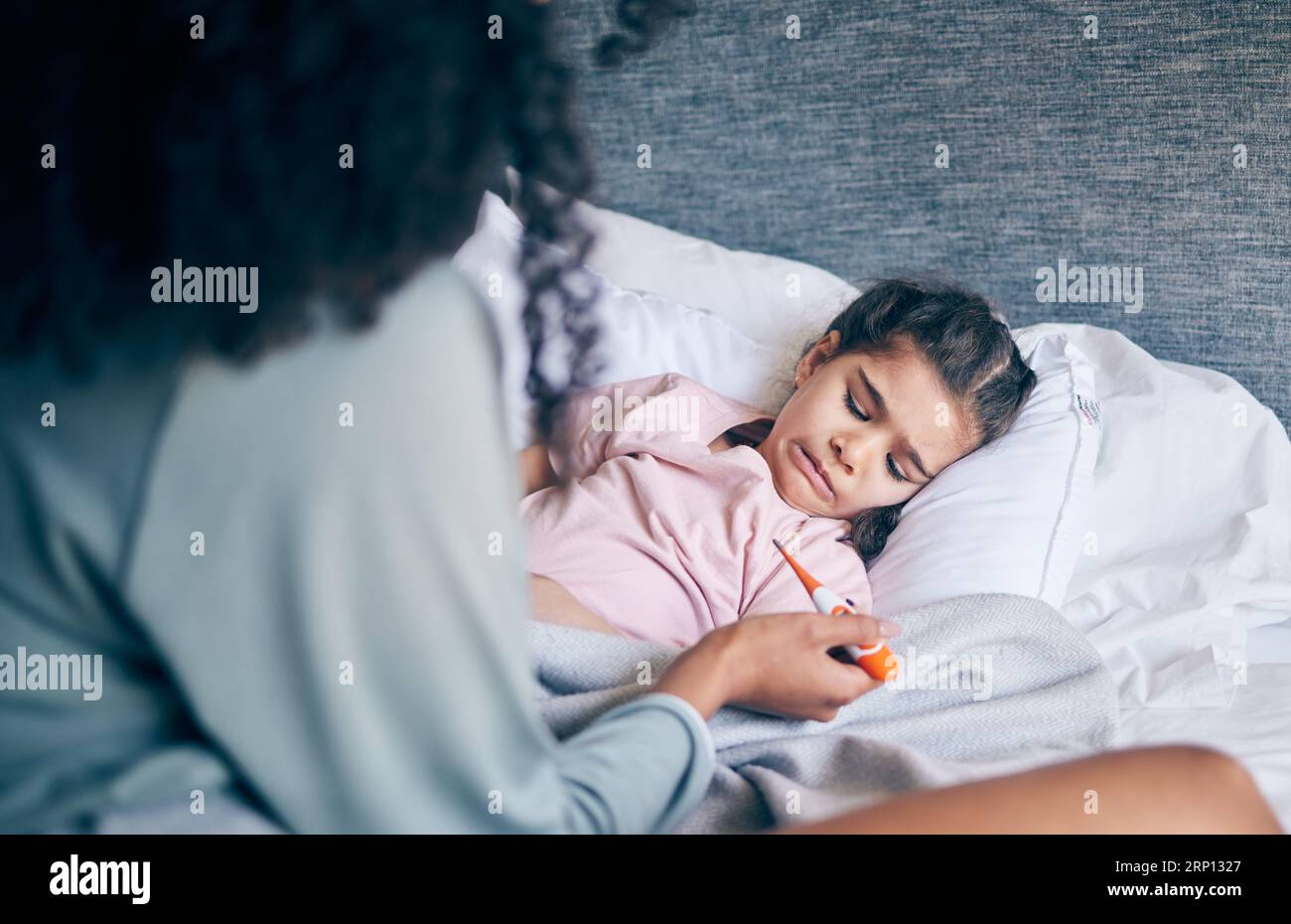 Mother, thermometer and sick child in bed with illness, virus or infection and caring parent at ...