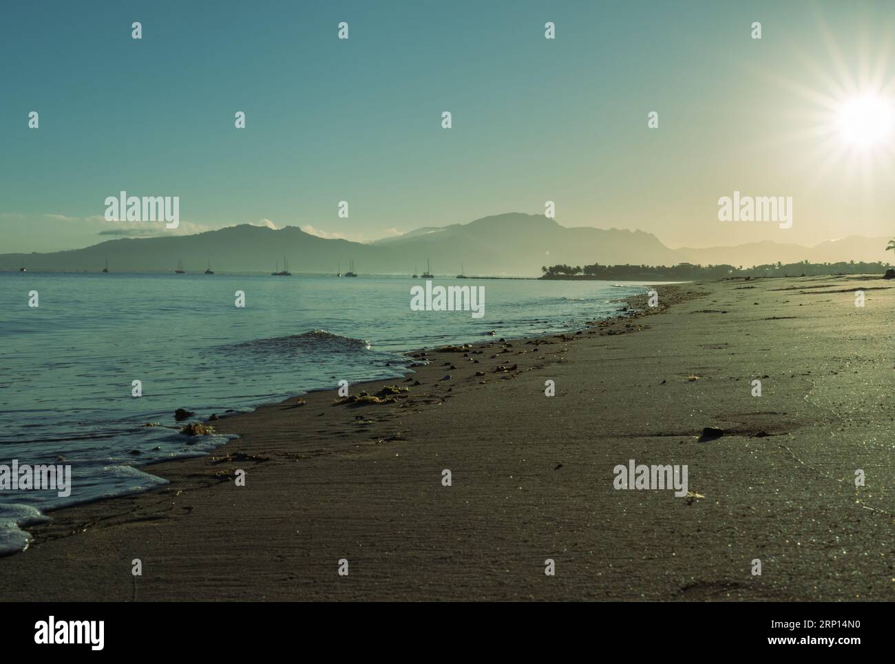 Idyllic tropical island beach scene at sunrise looking into sun Stock ...