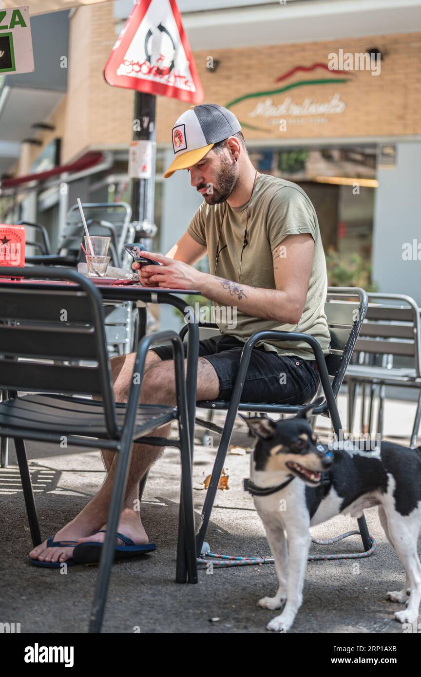 A young foreign man having a coffee on a terrace of a bar in summer ...