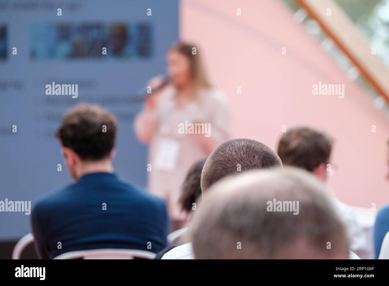 Back view of anonymous crowd of people gathering together and listening ...
