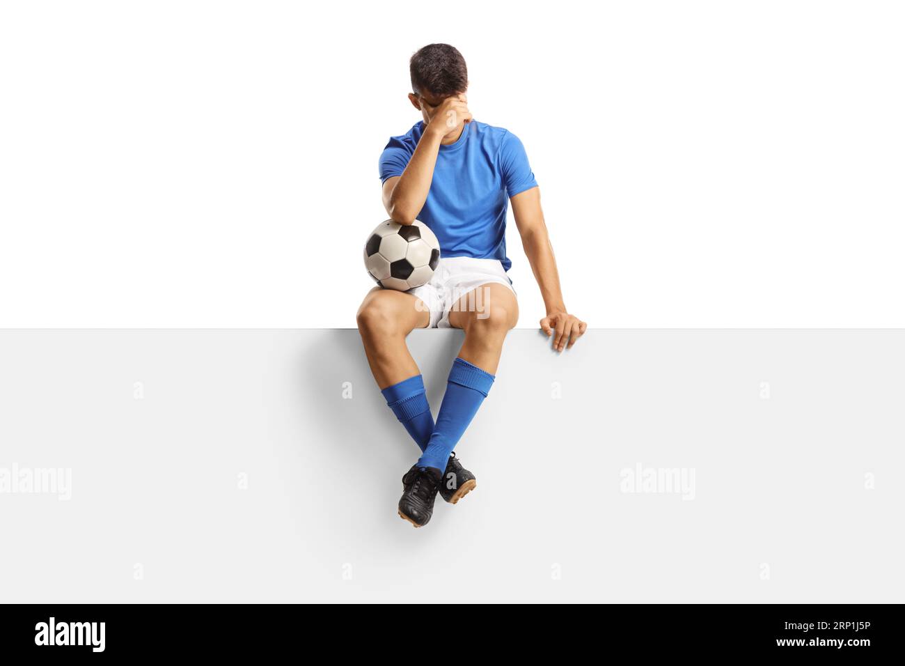Disappointed football player sitting on a blank panel isolated on white ...