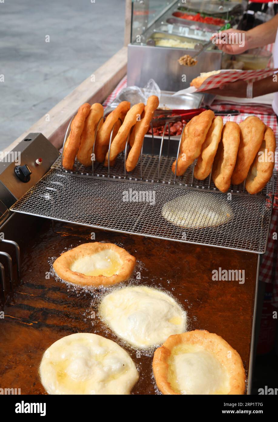 pancakes fried in boiling oil in the street food stall during the ...