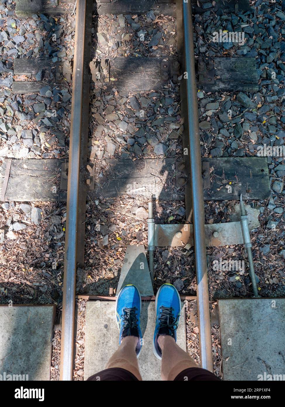Railroad rails and feet with running sneakers. Upper view down to legs ...