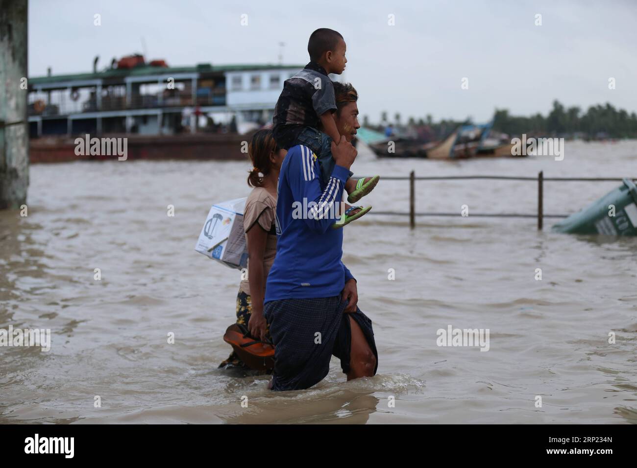 (180814) -- YANGON, Aug. 14, 2018 -- A family wade through a flooded ...