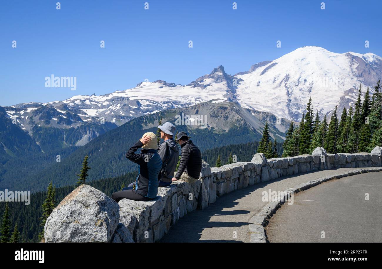 Three tourists sitting on the stone wall and enjoying the beautiful ...