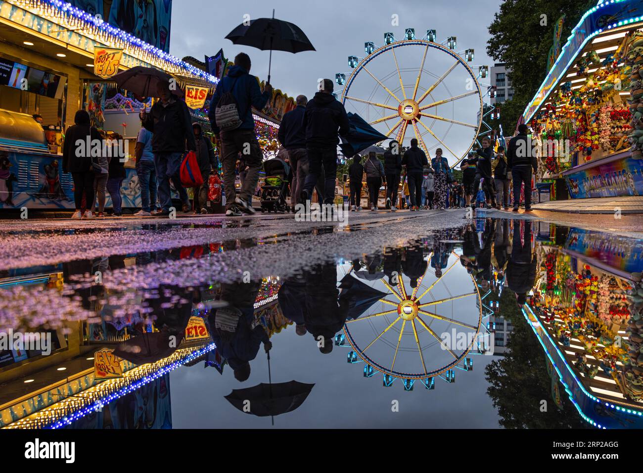 The colourful lights of the Mainfest are reflected in a puddle. The ...