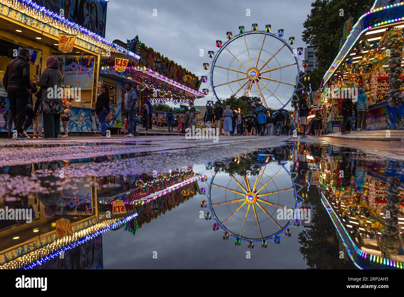 The colourful lights of the Mainfest are reflected in a puddle. The ...