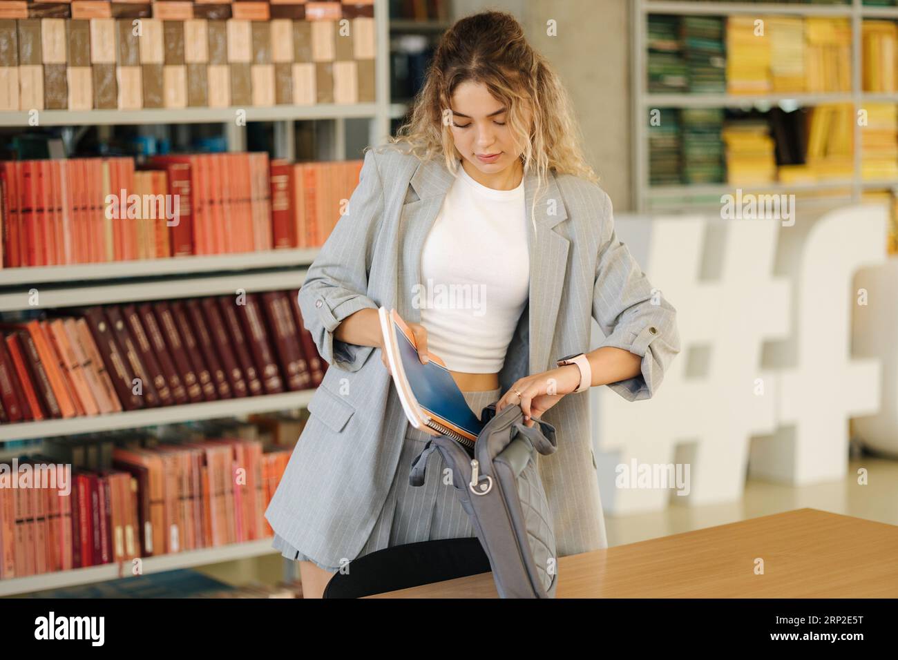 Female student finish study in public library and puts notebook in the ...