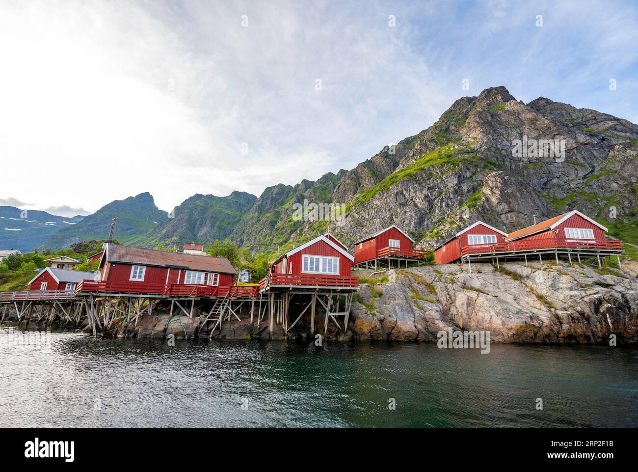 Traditional red rorbuer wooden cabins, on stilts on the shore, fishing ...