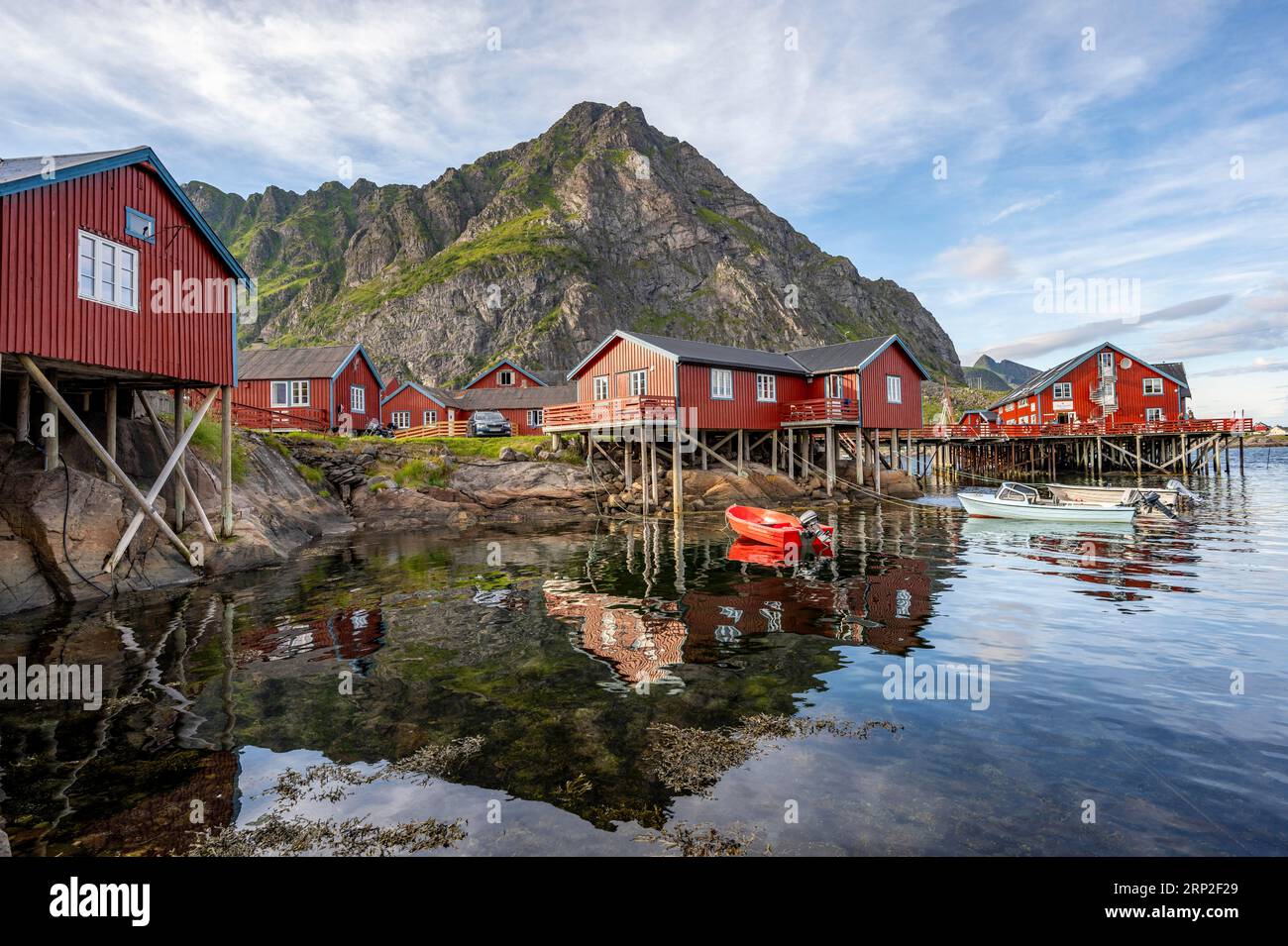 Traditional red rorbuer wooden huts, on stilts on the shore, reflected ...