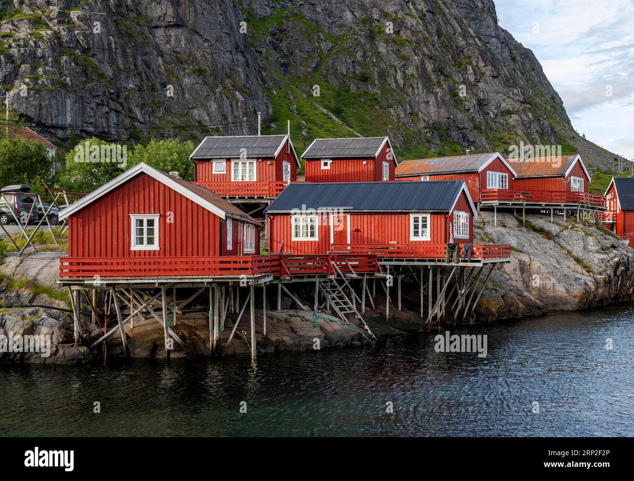 Traditional red rorbuer wooden cabins, on stilts on the shore, fishing ...