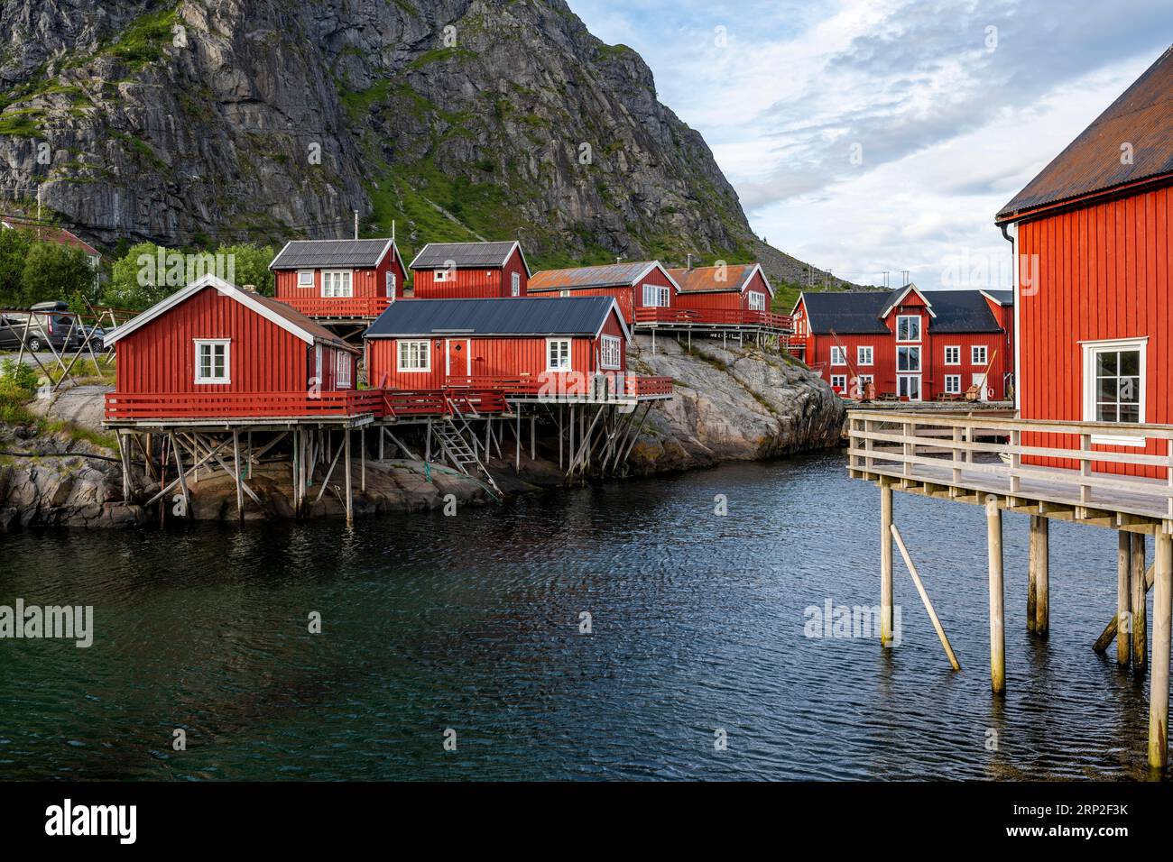 Traditional red rorbuer wooden cabins, on stilts on the shore, fishing ...
