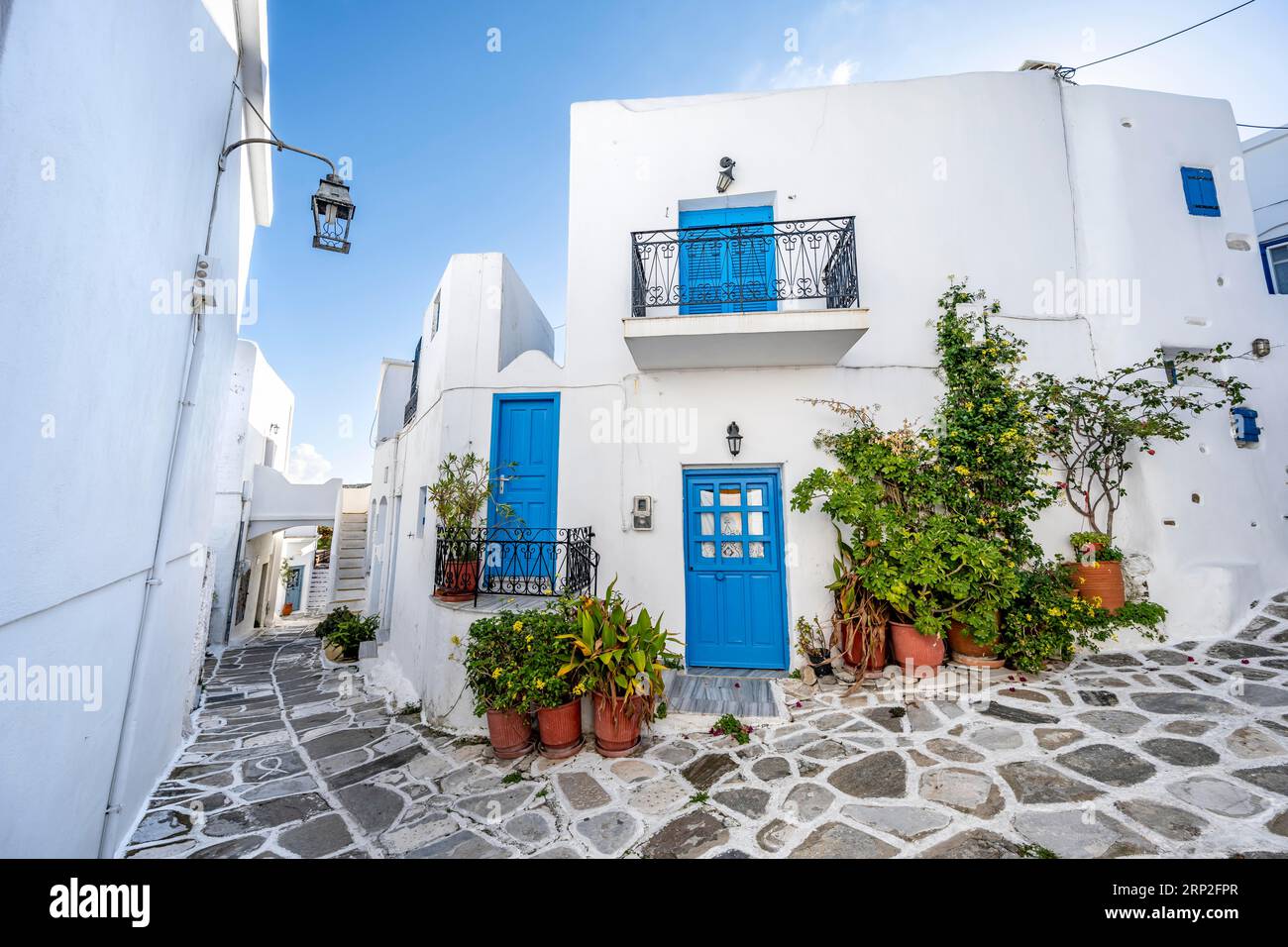 White Cycladic houses with blue doors and windows and flower pots ...