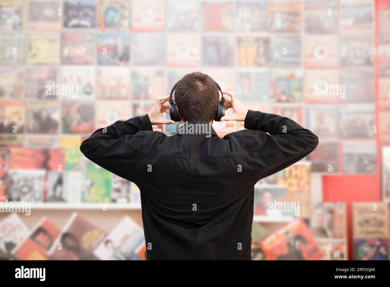 Medium shot back view young man listening music store Stock Photo - Alamy