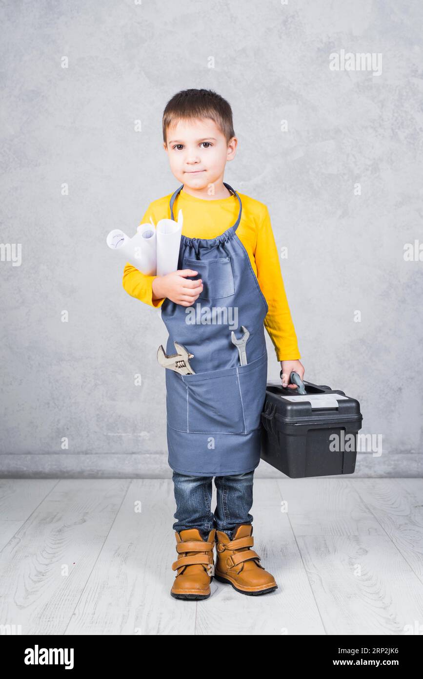 Cute boy standing with tool box paper rolls Stock Photo - Alamy