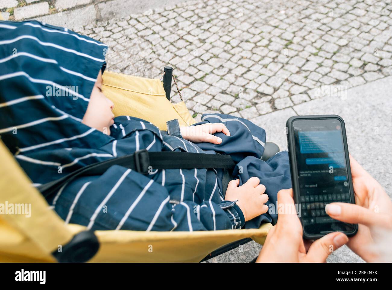 A woman corresponds via text messages in a messenger near a stroller ...