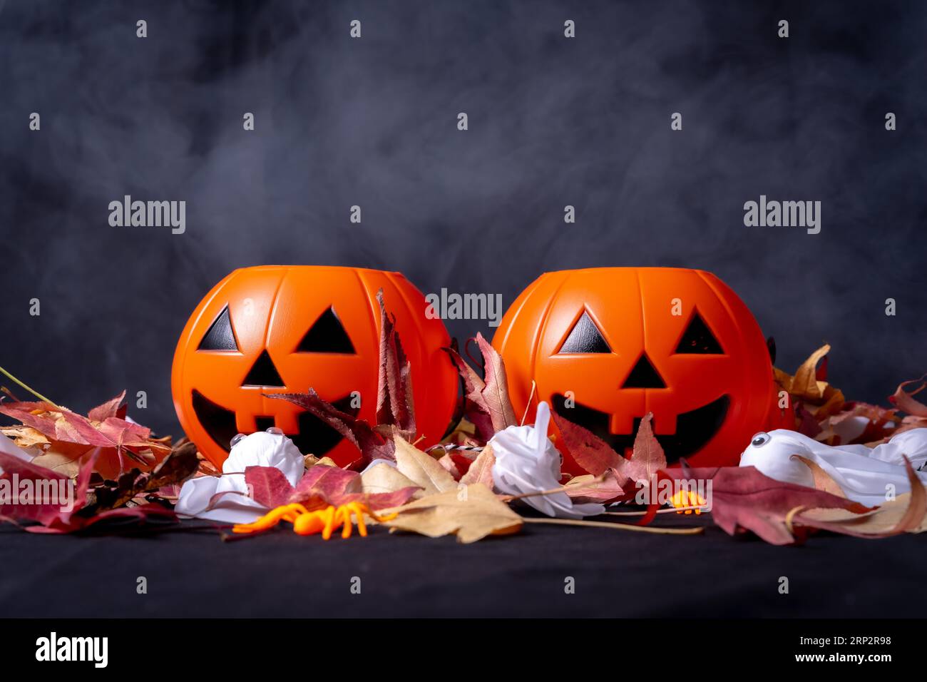Halloween pumpkins over red autumn leaves and ghosts with smoke on a ...