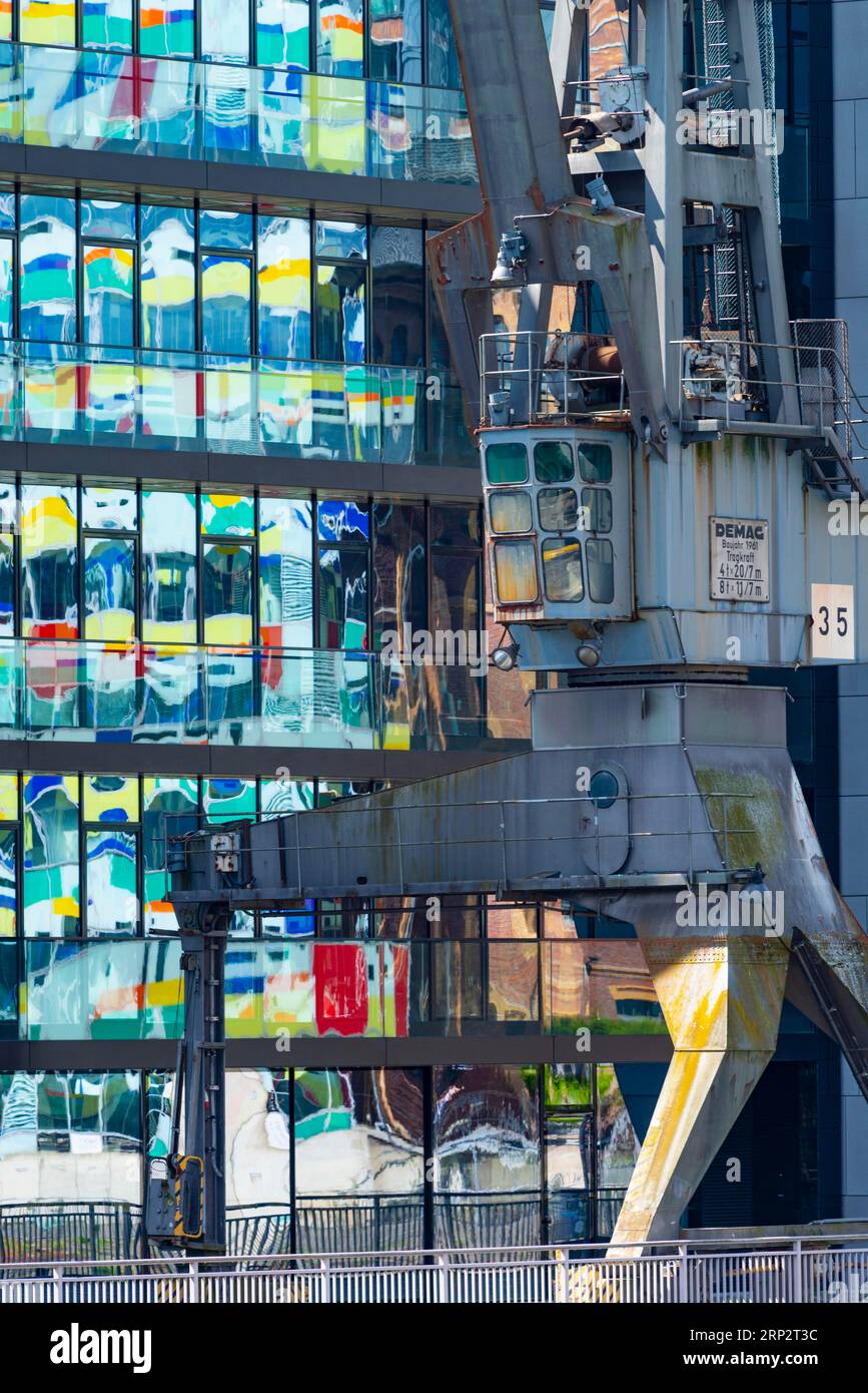 Old cargo crane in front of the glass facade of an office building ...