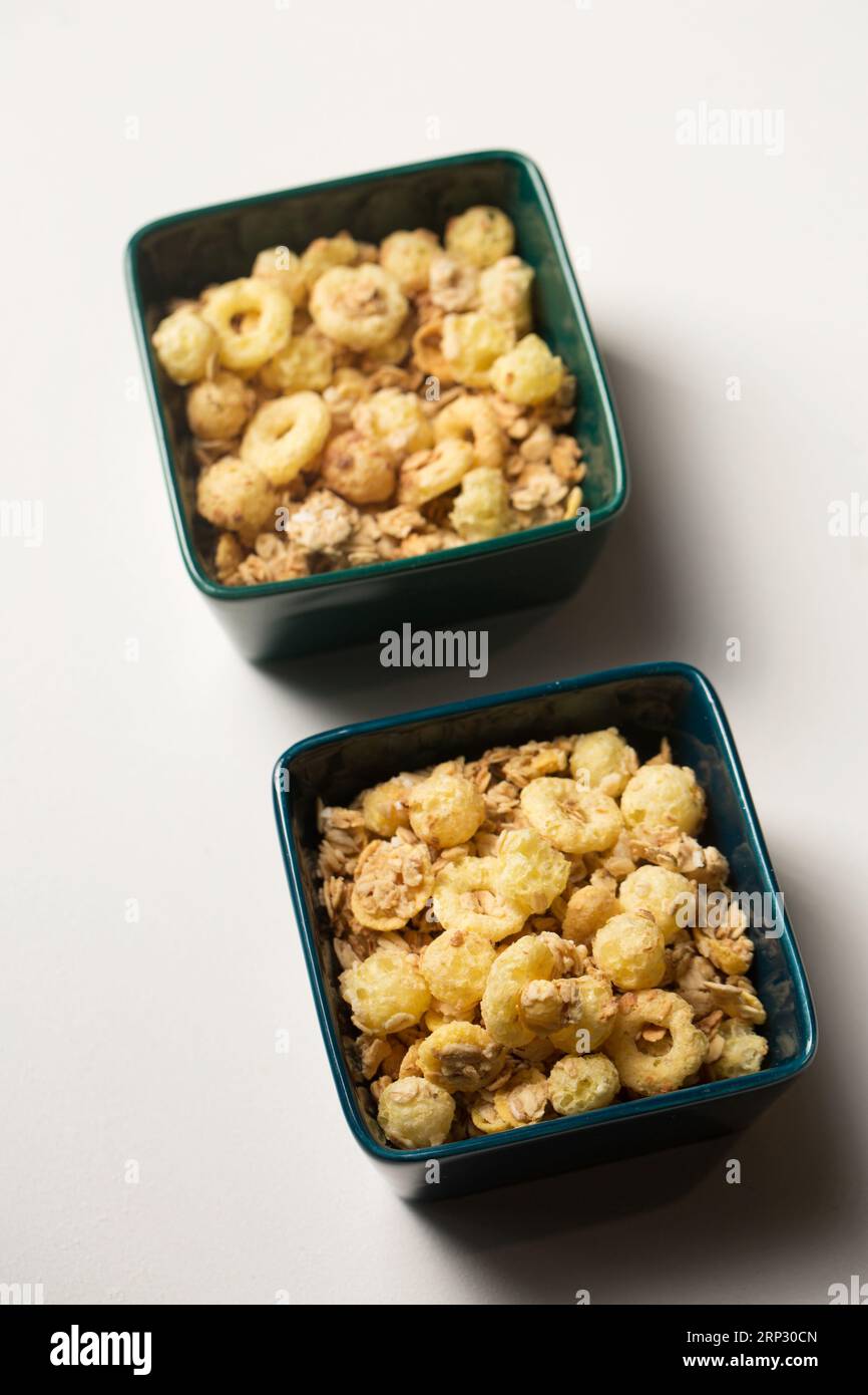 Breakfast cereal with granola and corn rings in small bowls on a white ...