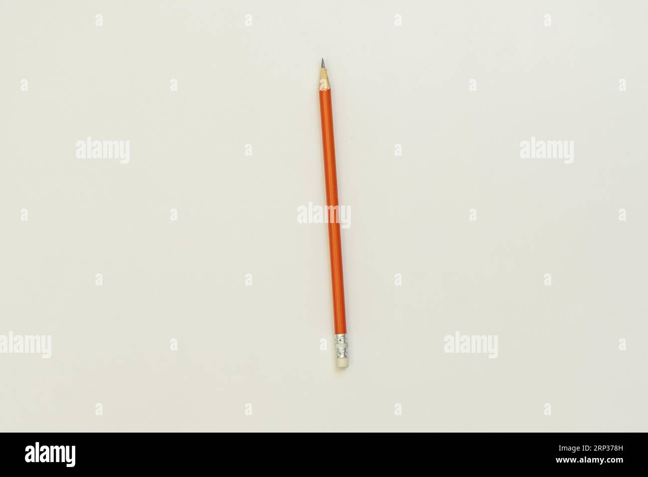 A sharp orange pencil with a small eraser on one end on a smooth white ...