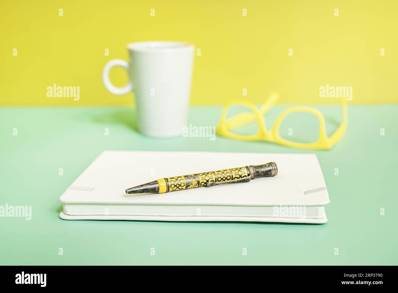 A bright and colorful image of a note pad with a pen and yellow glasses ...