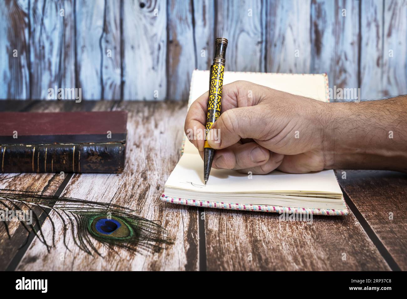 A man's hand writing in a small notebook with knitted covers with a ...
