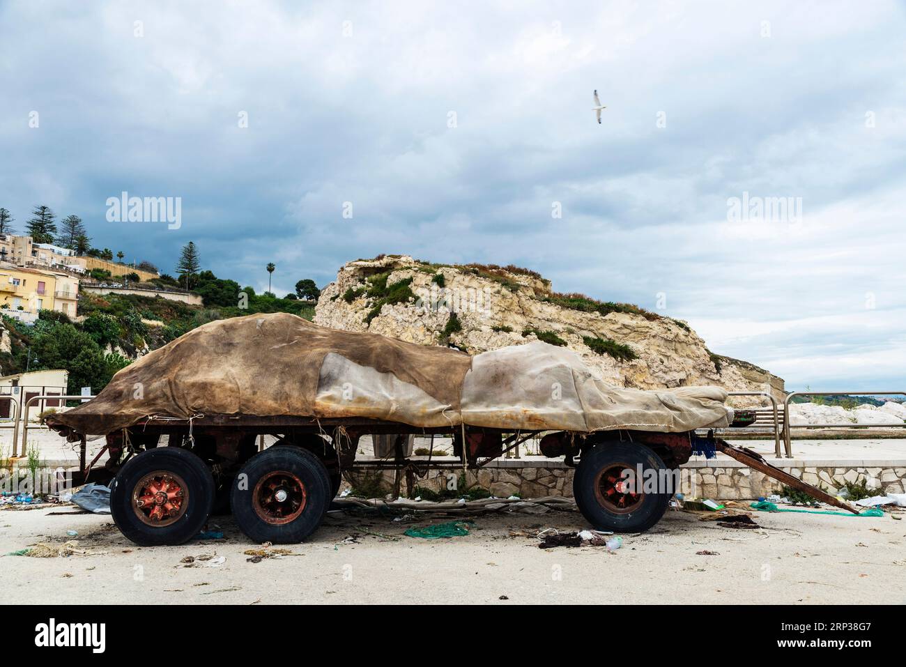 Old and abandoned trailer with a tarp on top in the port of Sciacca ...