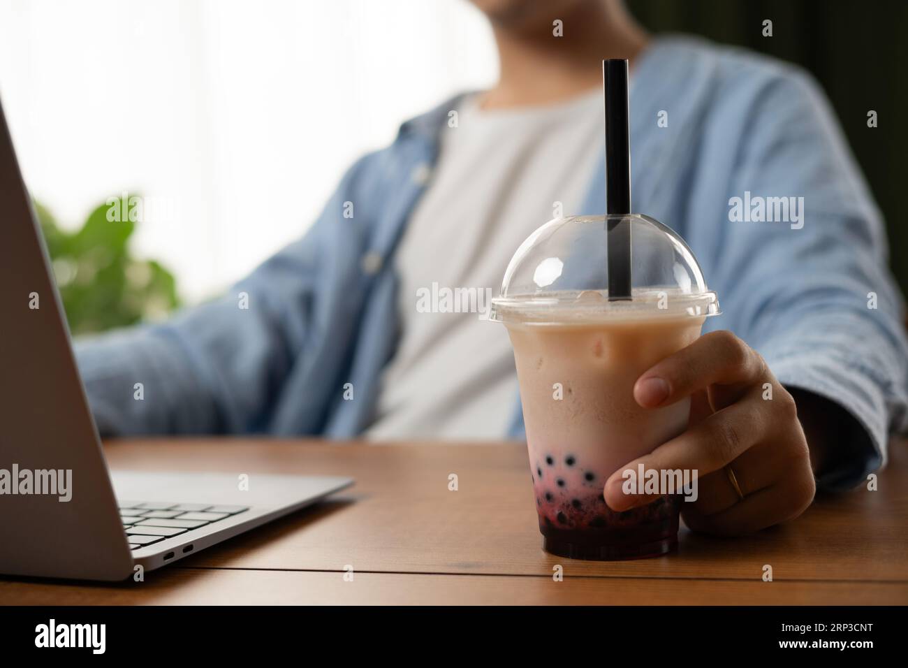 Asian young man working use laptop computer and drink bubble tea in ...