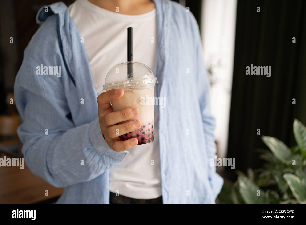 Young man look away and drink bubble tea in the restaurant Stock Photo ...