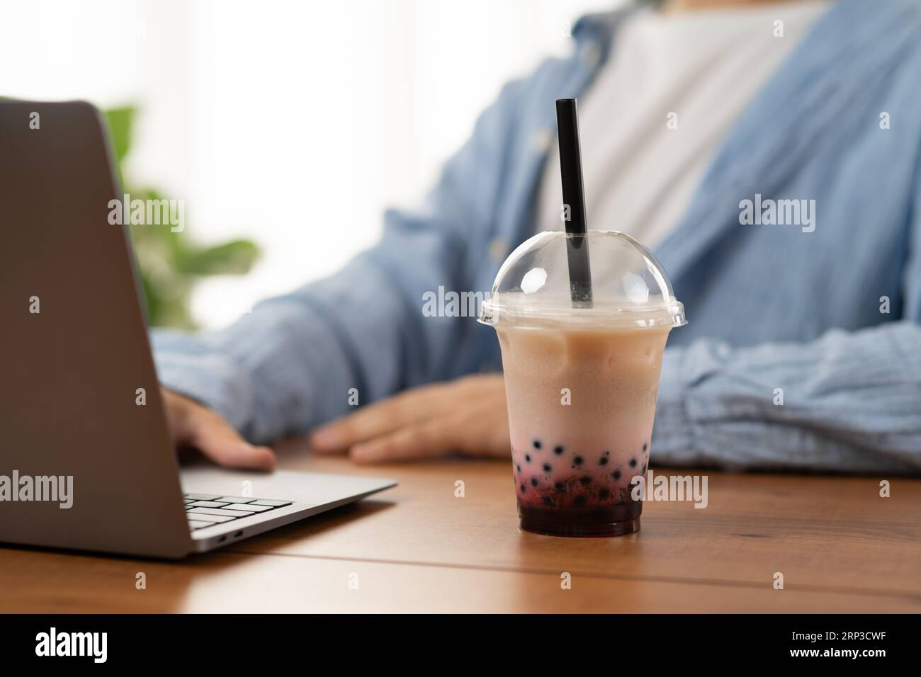 Asian young man working use laptop computer and drink bubble tea in ...
