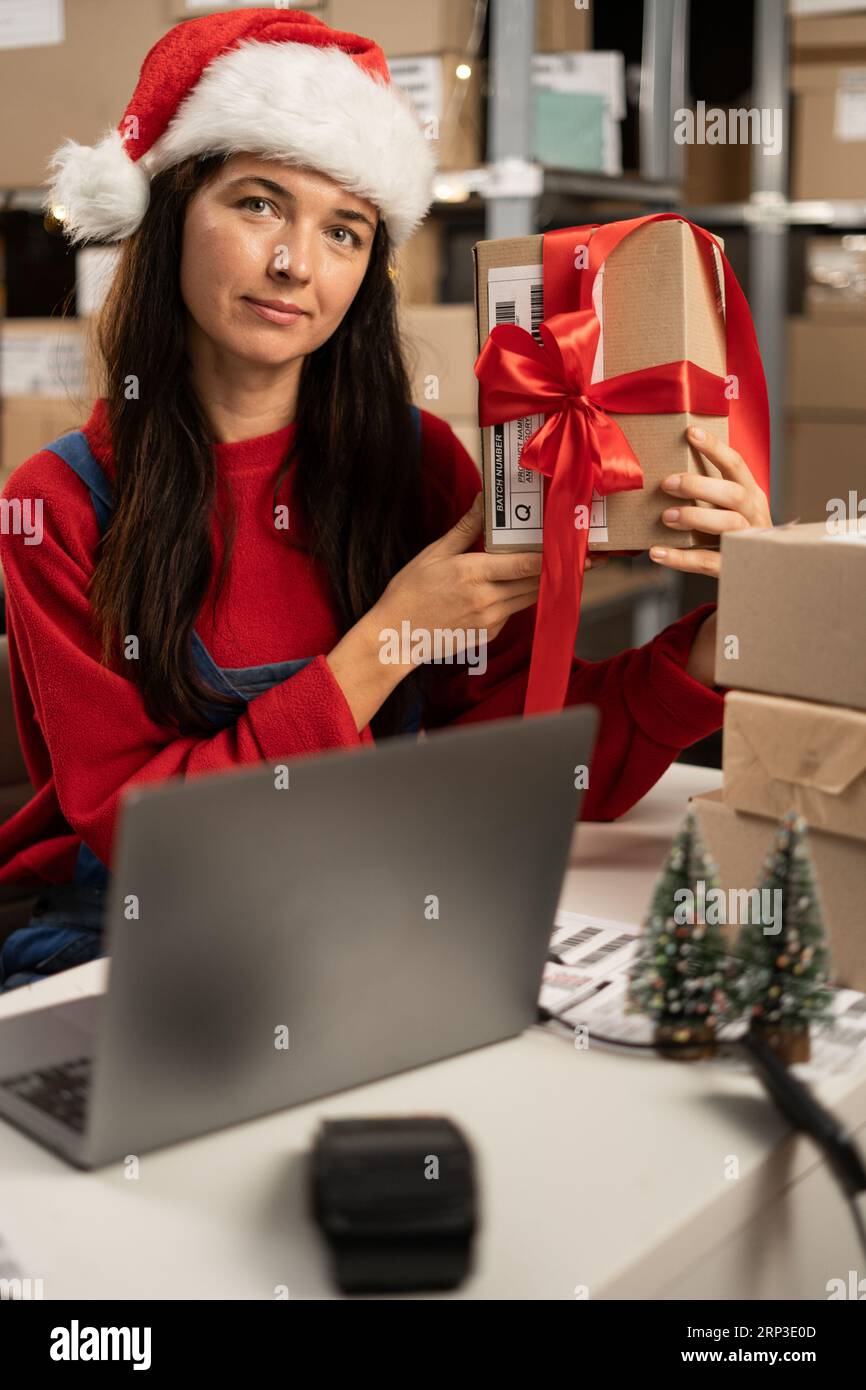 Inventory manager preparing a gift parcel for postage. Young female small business owner working ...