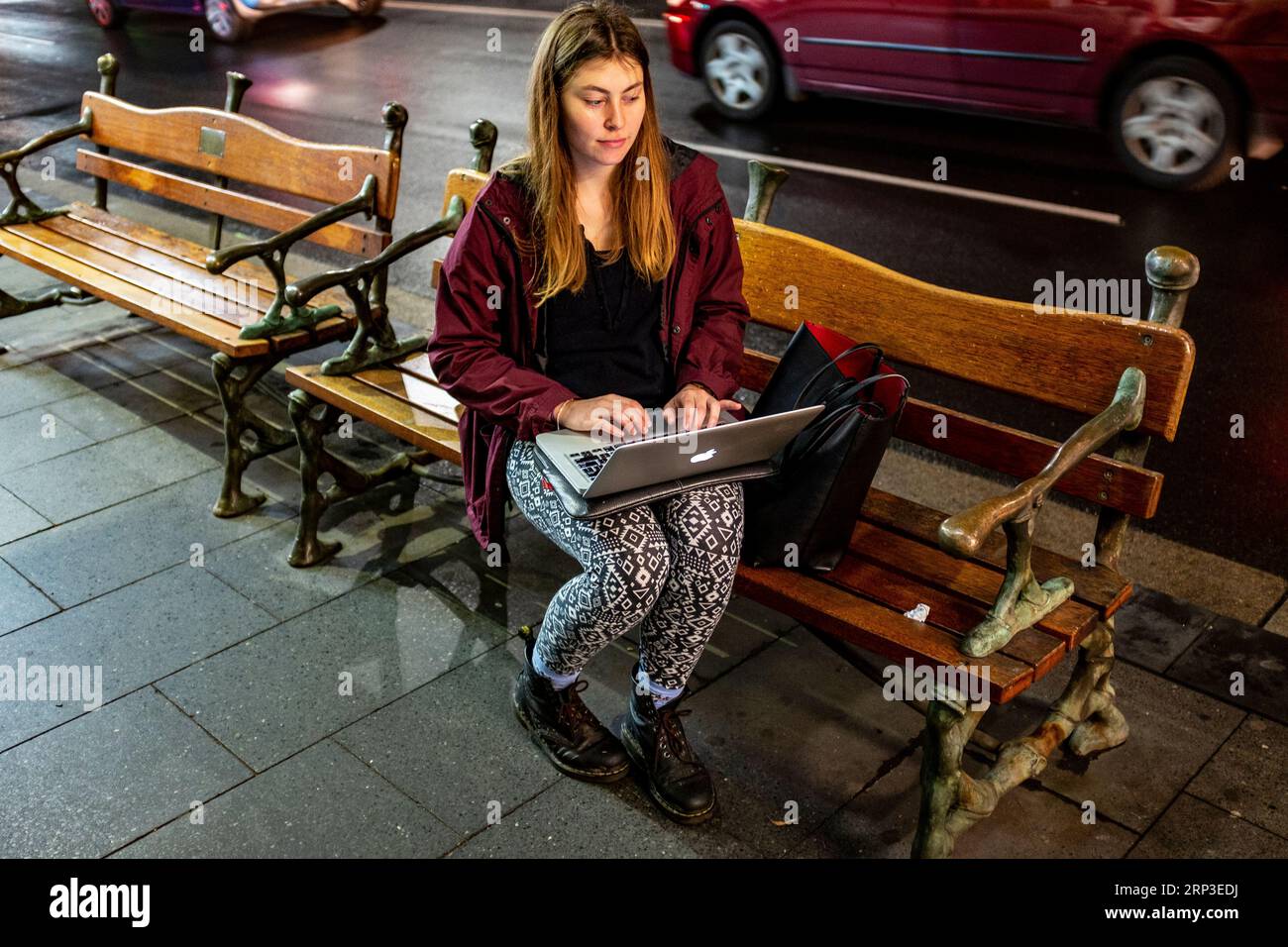 Young student doing homework, working on laptop at bus stop in Glebe ...
