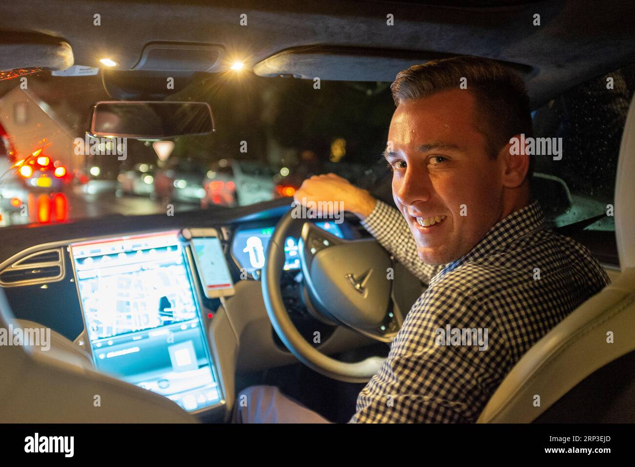 Uber driver the wheel of a Tesla EV at night in the rain Stock Photo ...