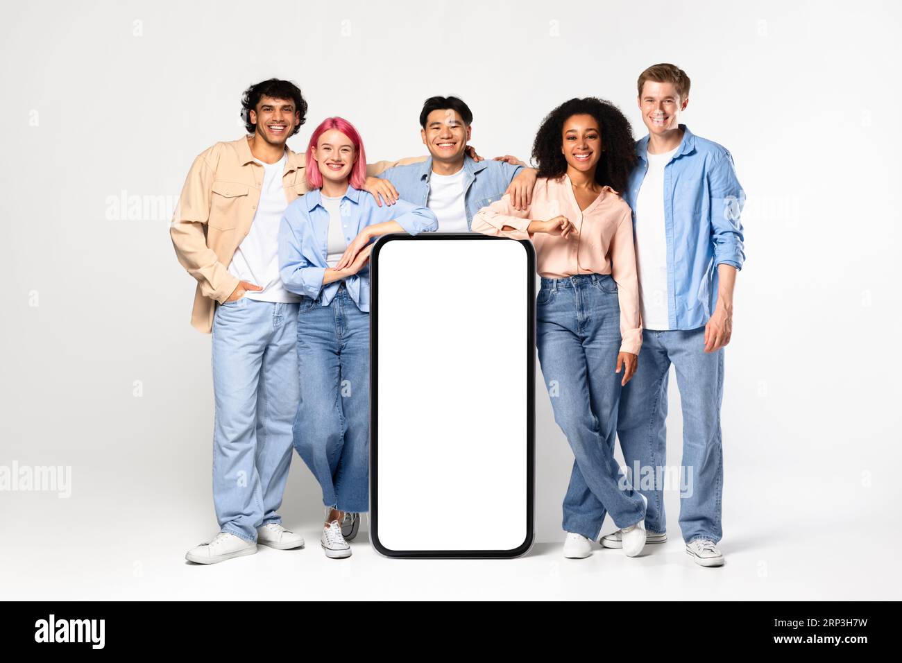 Happy diverse friends posing near big cellphone with white blank screen ...