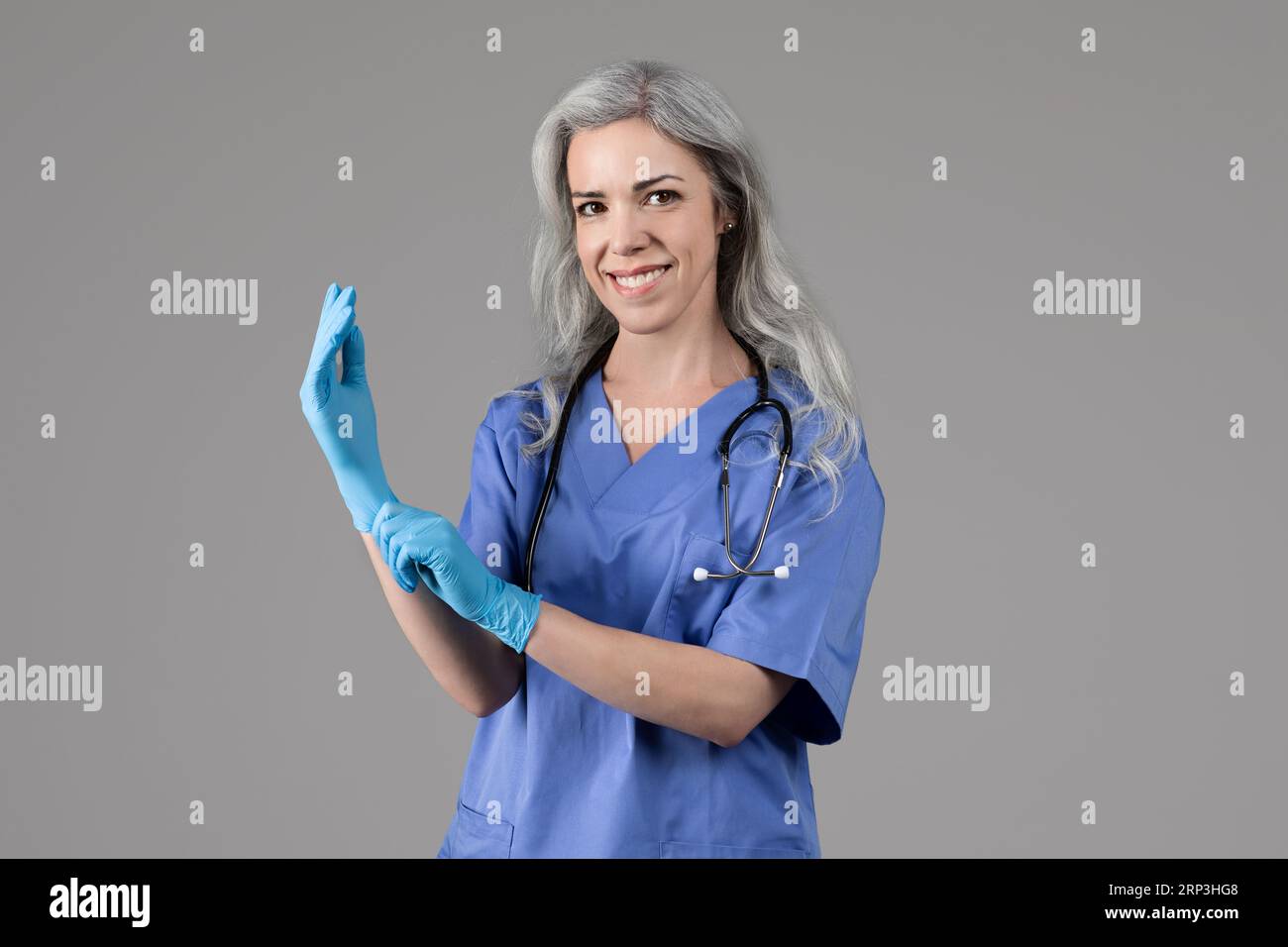 Smiling Nurse Woman Putting On Rubber Gloves On Gray Background Stock ...