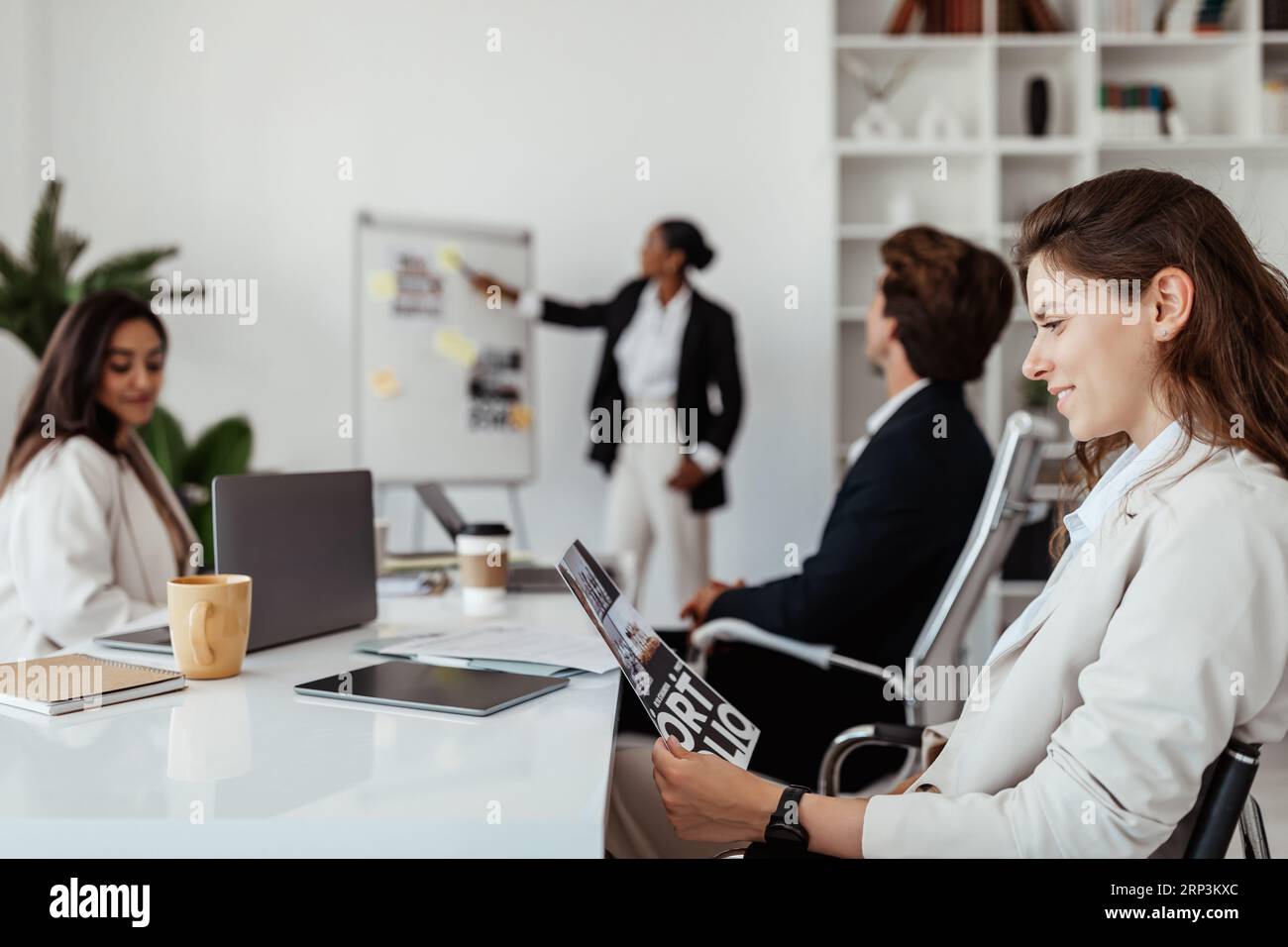 Happy female manager looking at magazine during corporate meeting ...