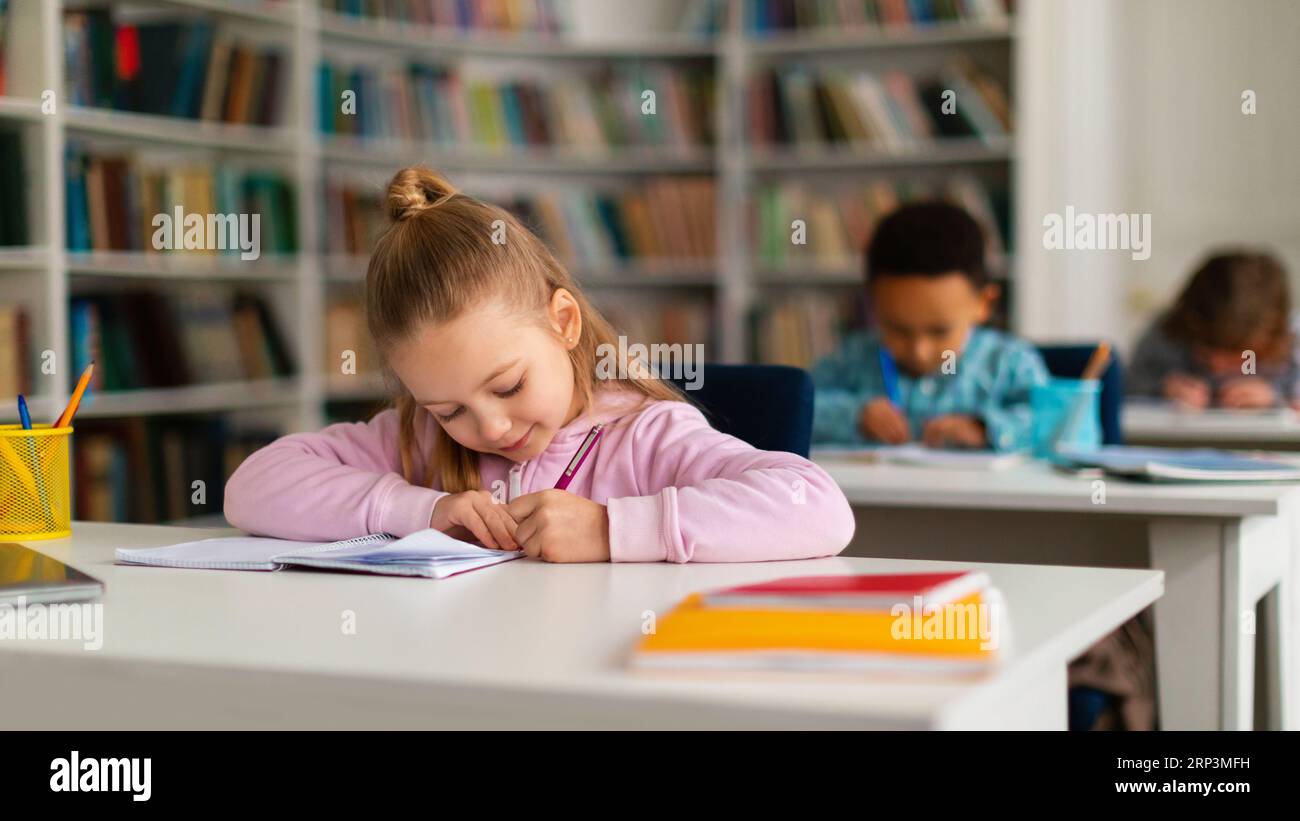 School children sitting at desks in classroom interior, studying in ...