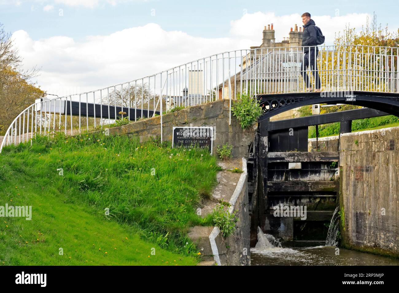 Young man crossing a footbridge and lock gates, Widcombe Lock, Kennet ...