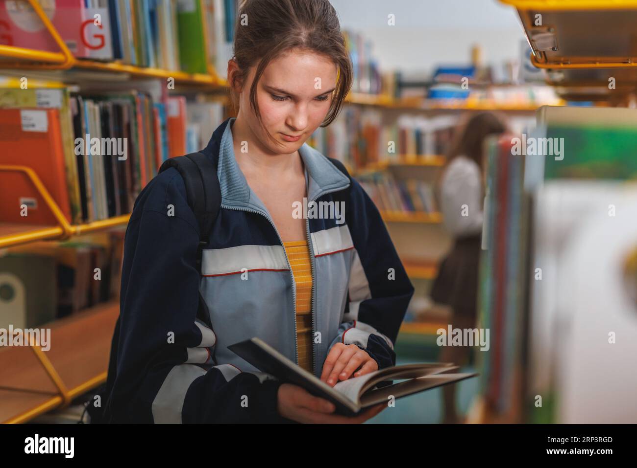 Girl student walking between shelves in the library focusing on a ...
