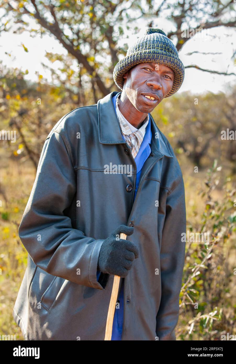 African Villager With A Beanie And Leather Jacket Holding A Stick Portrait Outdoors In The