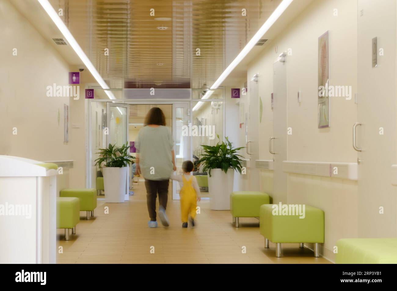Baby and mother are walking hand in hand down the long hospital ...