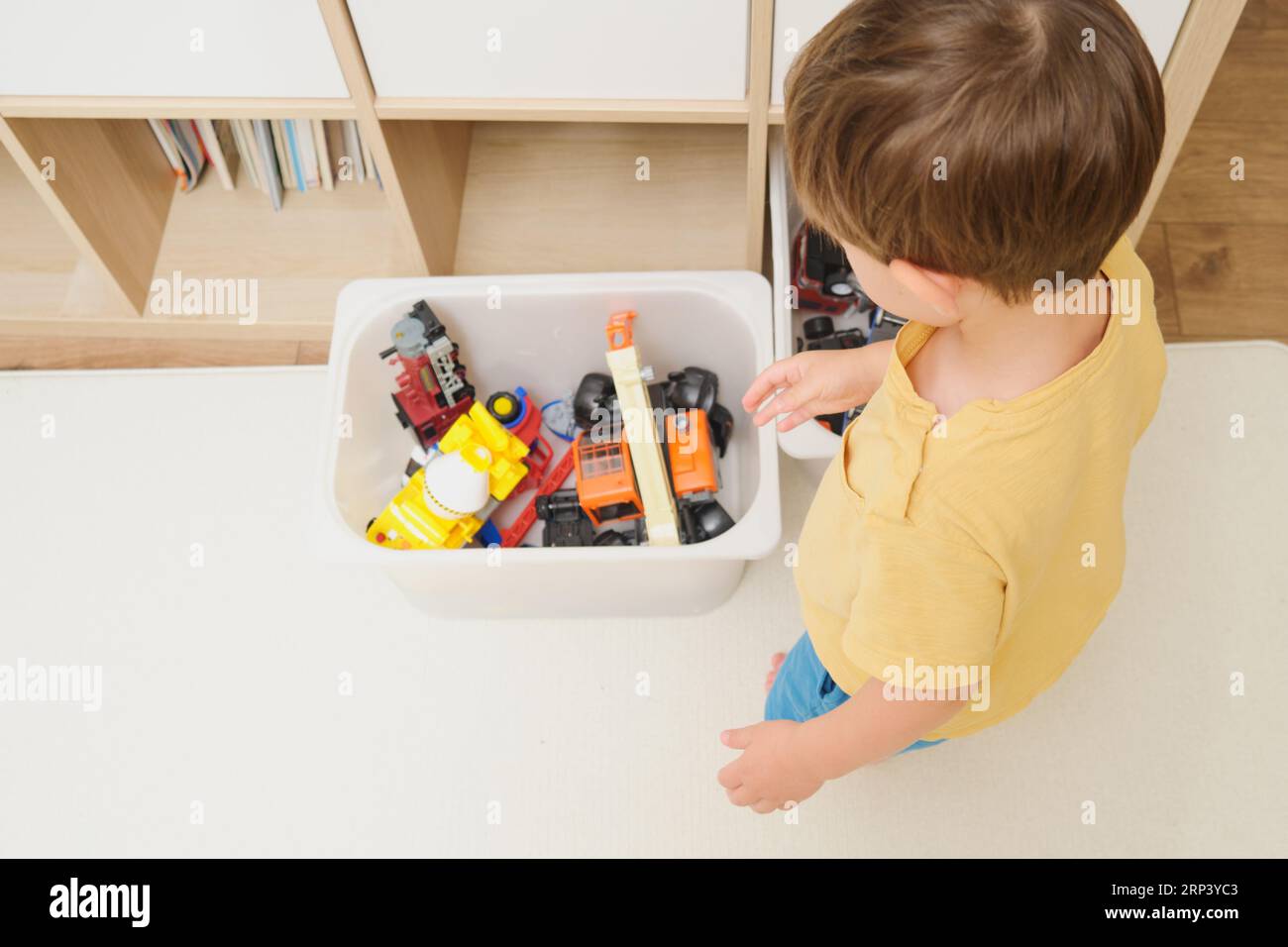 Child boy is organizing his room by putting his toys in order. Kid ...