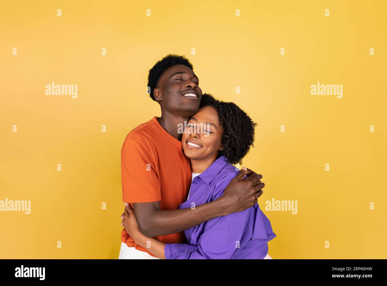 Happy millennial black guy hugging lady, enjoy love, isolated on yellow ...