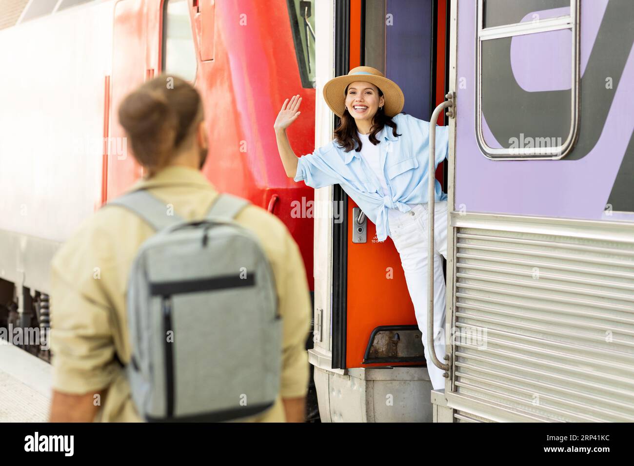 Young european guy meets glad woman, waving hand at train at station ...