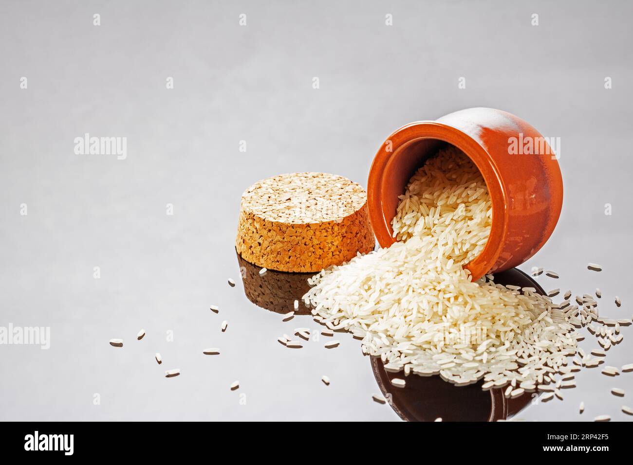 Rice spilled out of the pot on a mirror background Stock Photo - Alamy