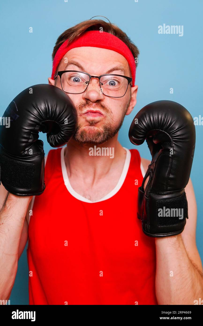 Angry funny male boxer in red sportwear standing wears boxing gloves ...
