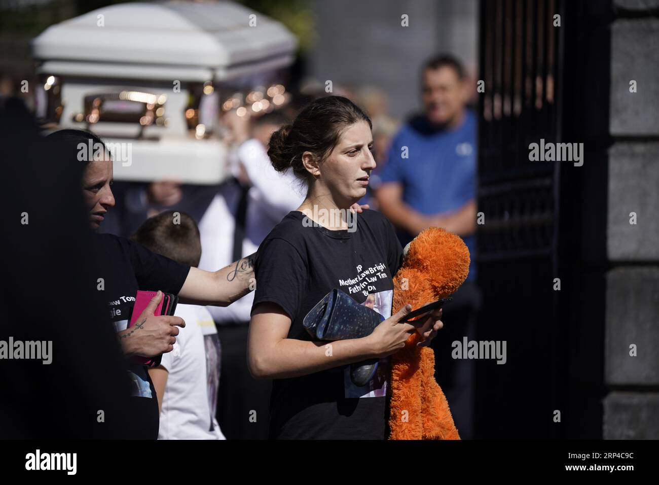 Diane Reilly (carrying orange toy) looks at the coffin of her three ...