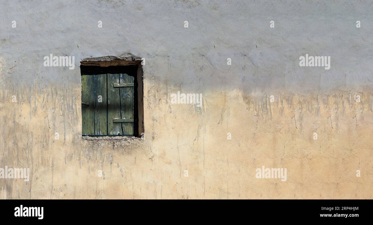 Aged wooden closed shutter on faded worn empty building stonewall ...